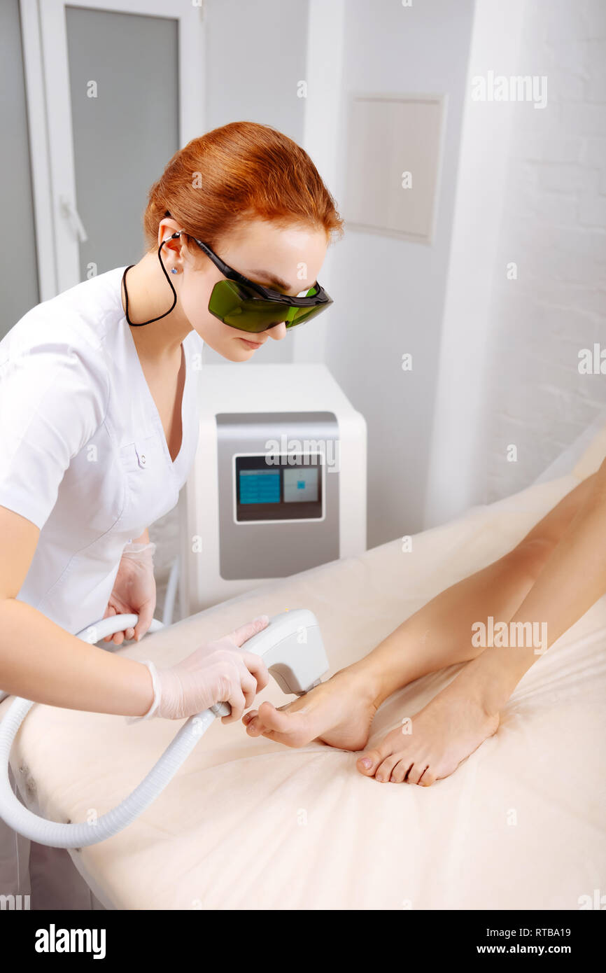 Master of photo depilation working with foot of her client Stock Photo ...