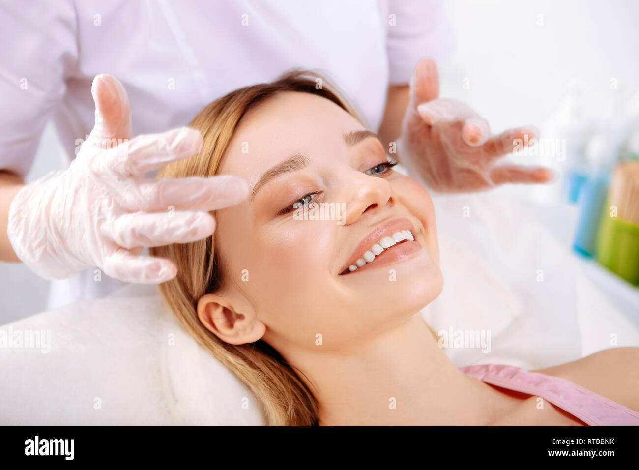 Cosmetologist making face massage of beautiful smiling client Stock ...