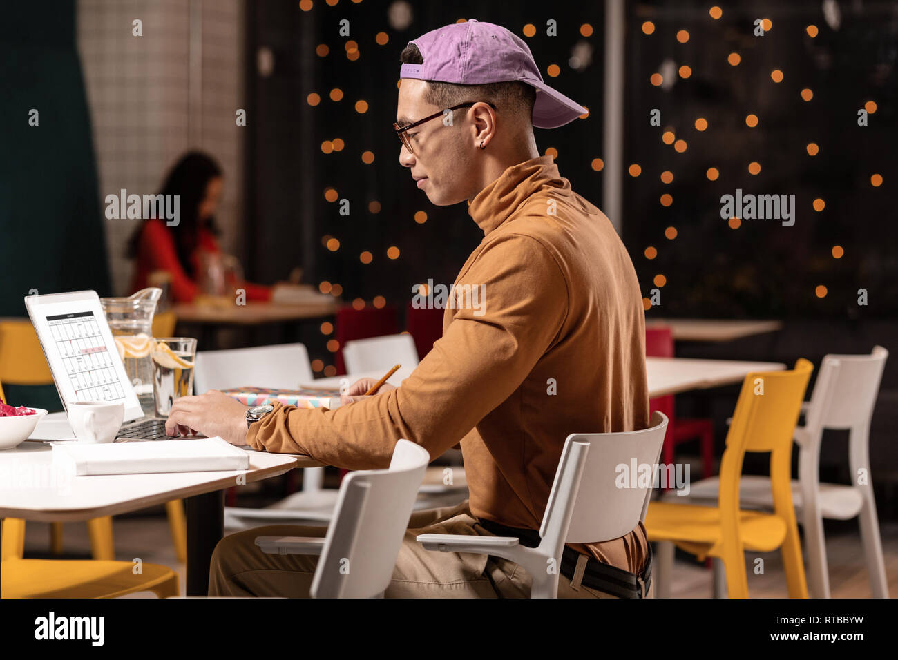 Boy in cap sitting in cafe and filling yearly report Stock Photo - Alamy