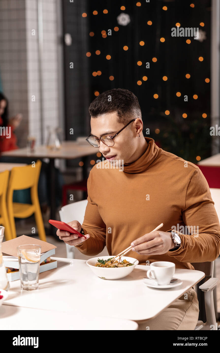 Young African American man distracting from eating with phone call ...
