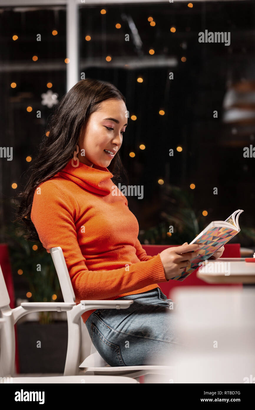 Asian girl reading book in cozy atmospheric cafe with fairy lights on ...