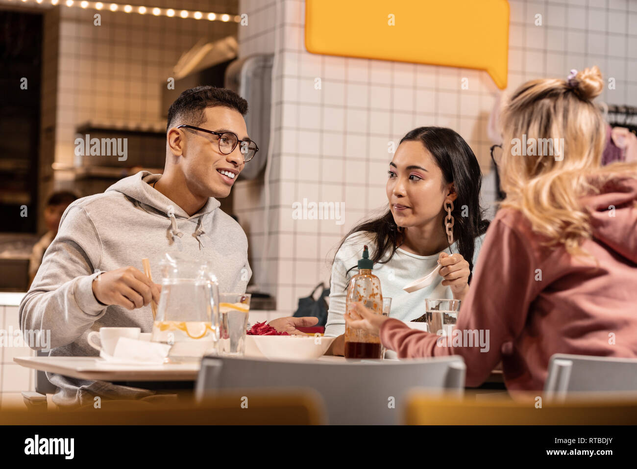 Three friends eating in local cafeteria with exotic cuisine Stock Photo ...