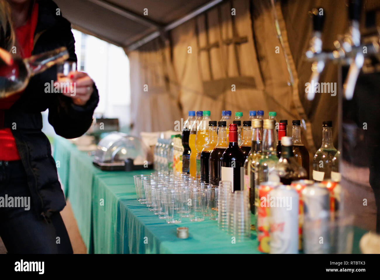 Waitress serves alcoholic drinks under a tent with a table full of ...