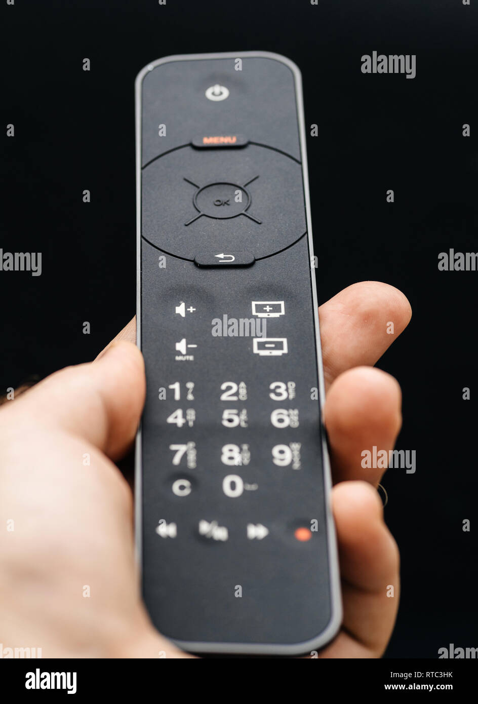 Man hand holding television remote control against black background ...