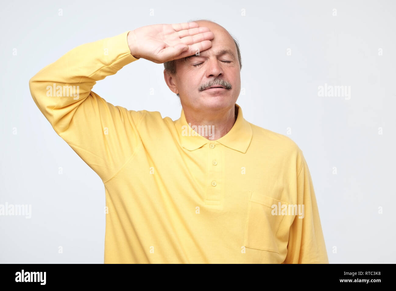 Exhausted european senior man wipes the sweat of his forehead. He has ...