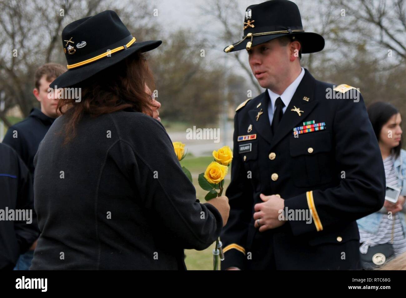 Cpt. Daniel Oberlander, the emcee for the memorial, offers yellow roses ...