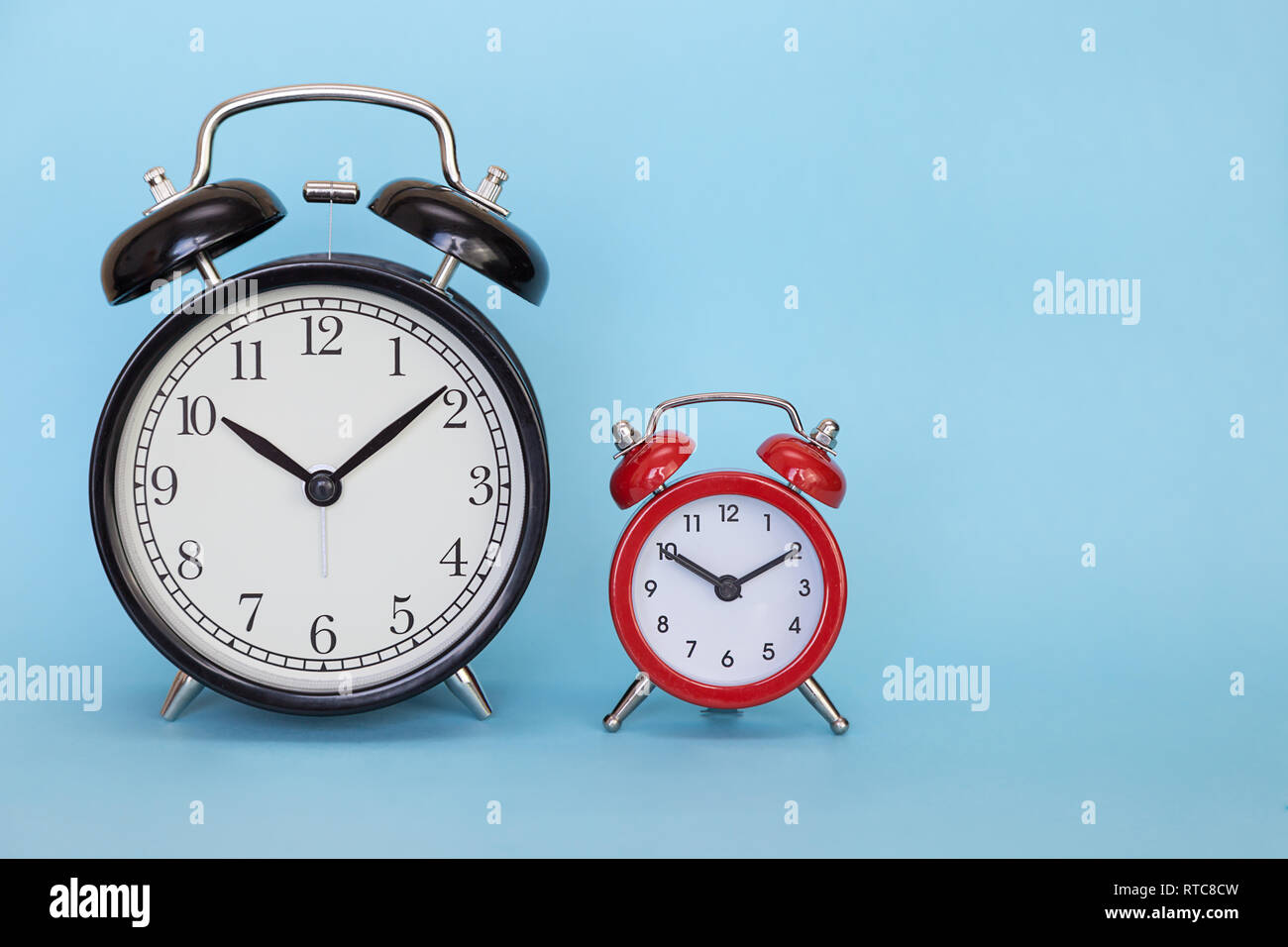 two red and black retro alarm clocks on a blue background with free ...