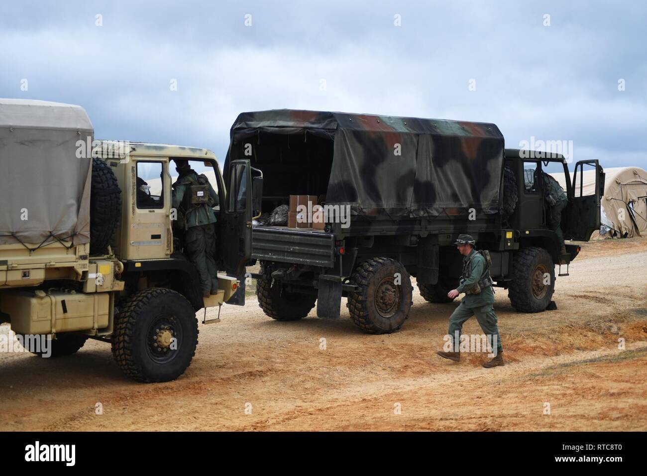 U.S. Army Soldiers drive cargo trucks through the Geronimo Landing Zone ...
