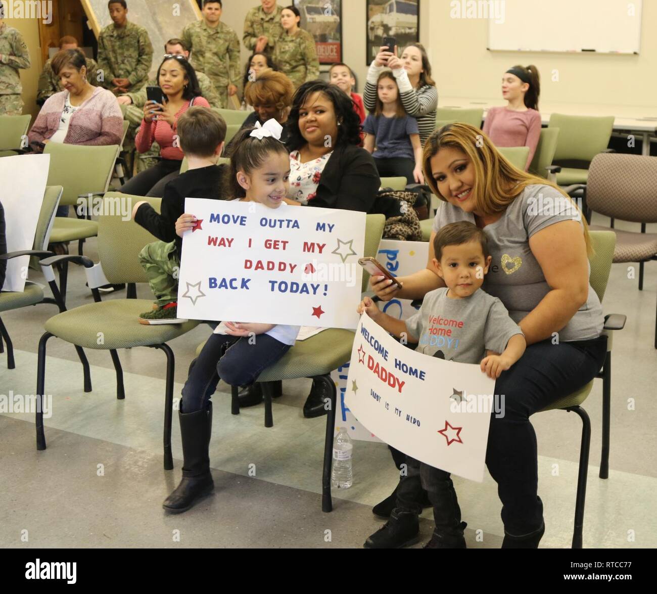 Family members hold up signs welcoming home soldiers from 60th ...