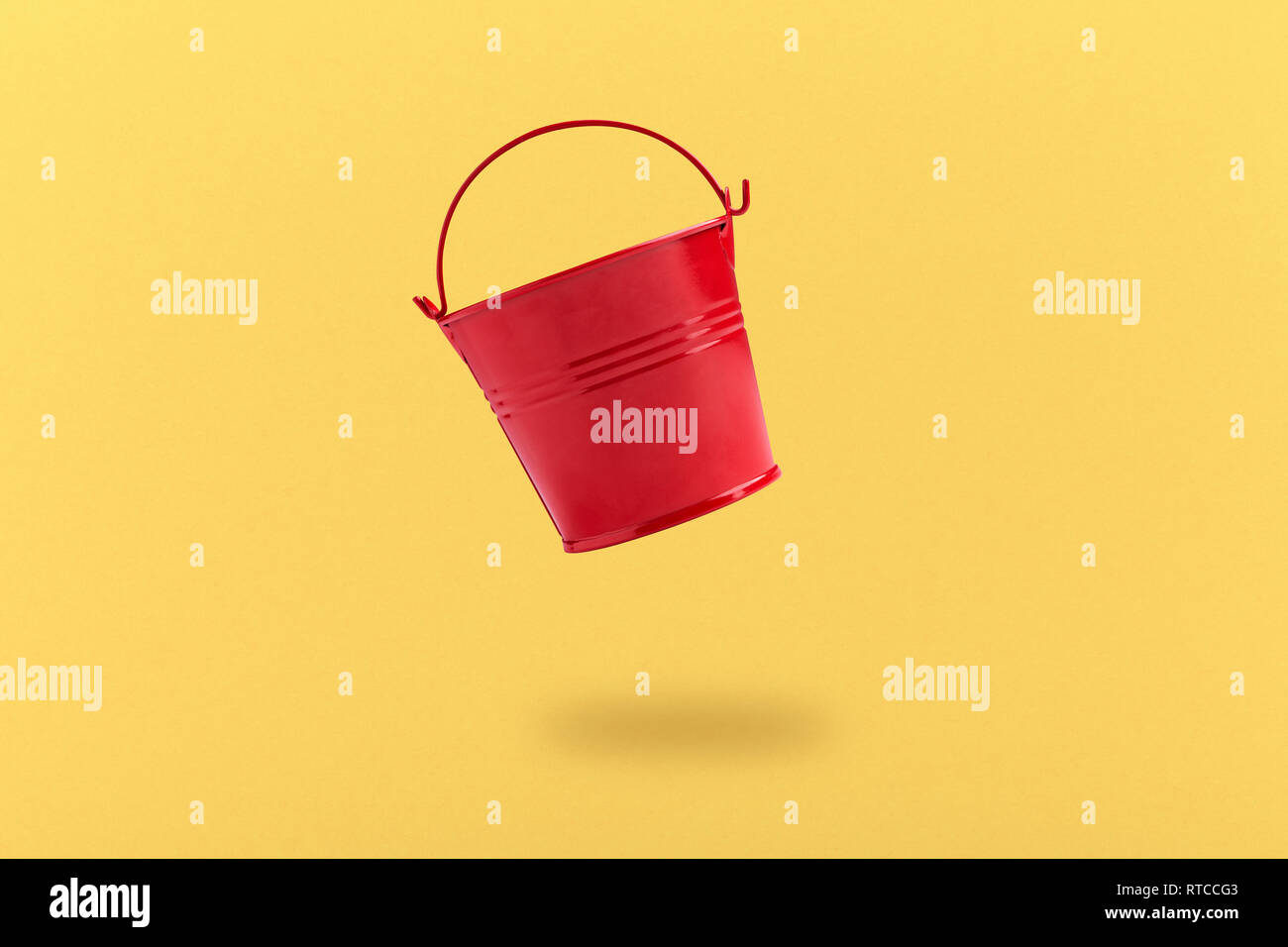 levitating red iron bucket, image on a yellow background Stock Photo ...