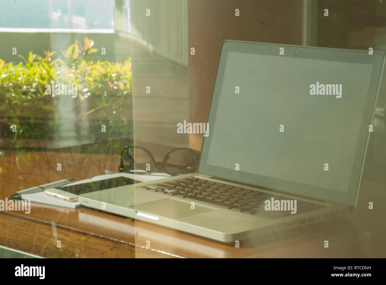 Reflections of laptops, glasses, mobile phones, notebooks and pens on ...
