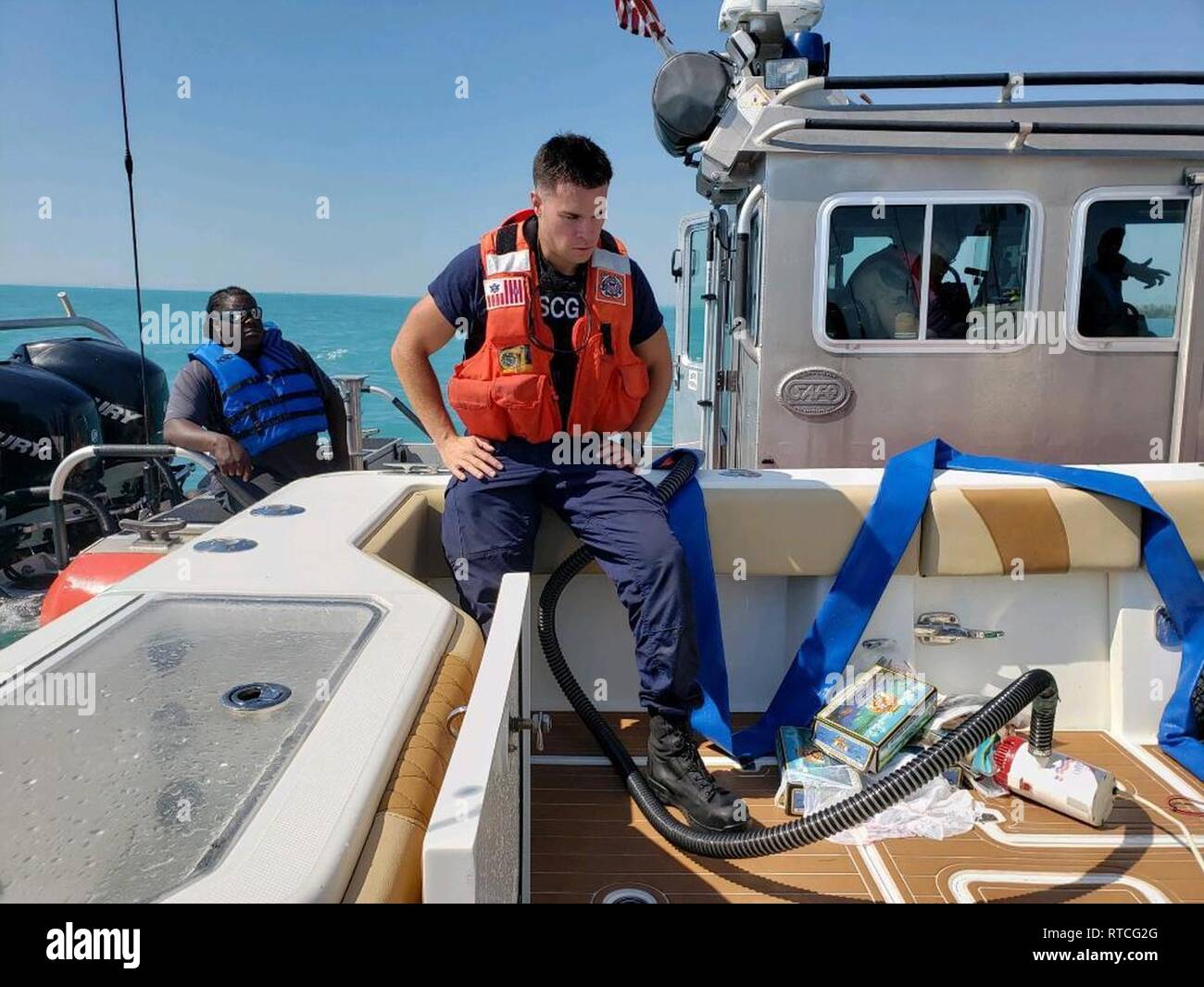 A Coast Guard Station Marathon crewmember assists in dewatering a 39 ...