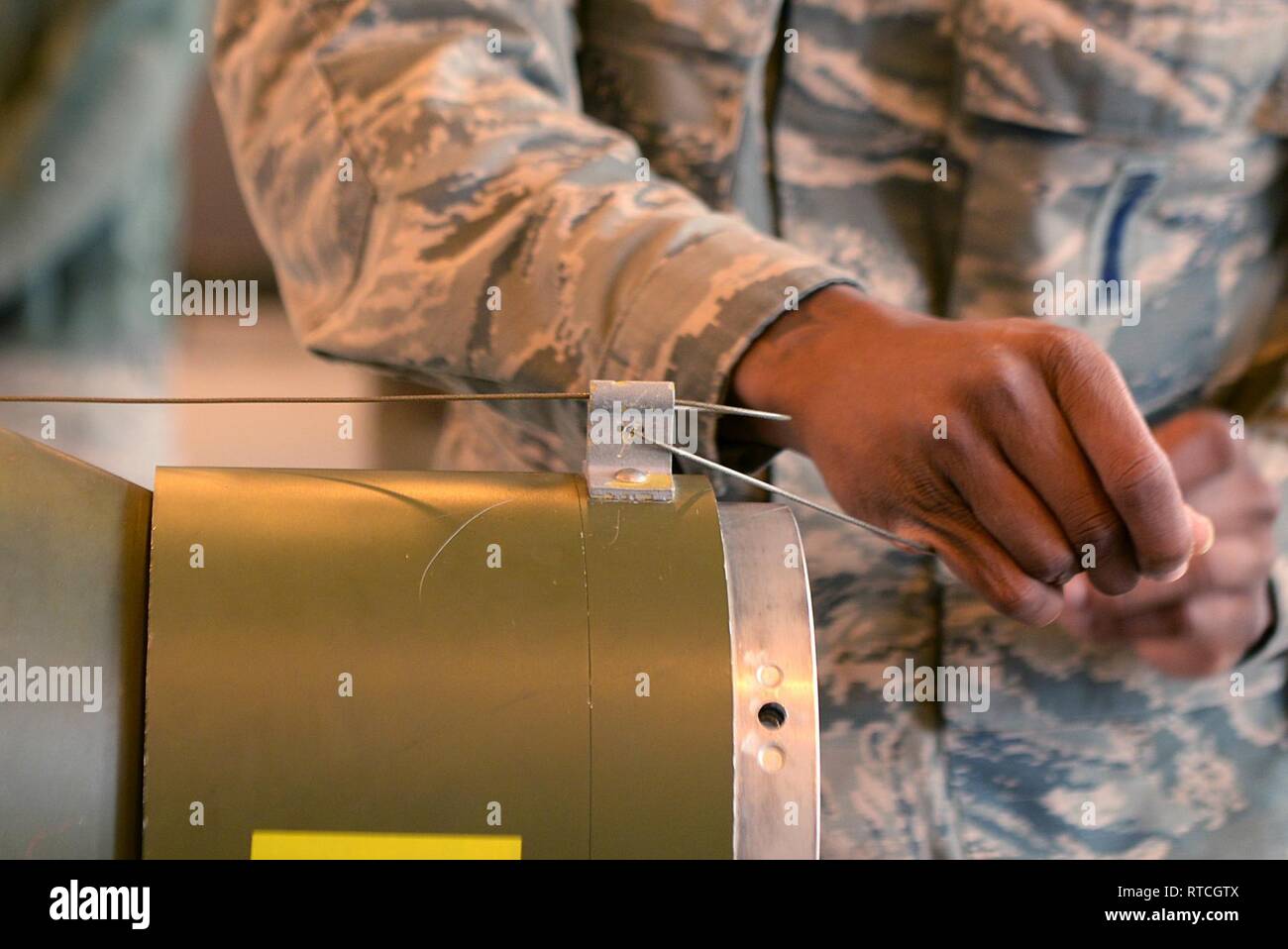 A weapons load crew member tightens an arming lanyard on a training GBU ...