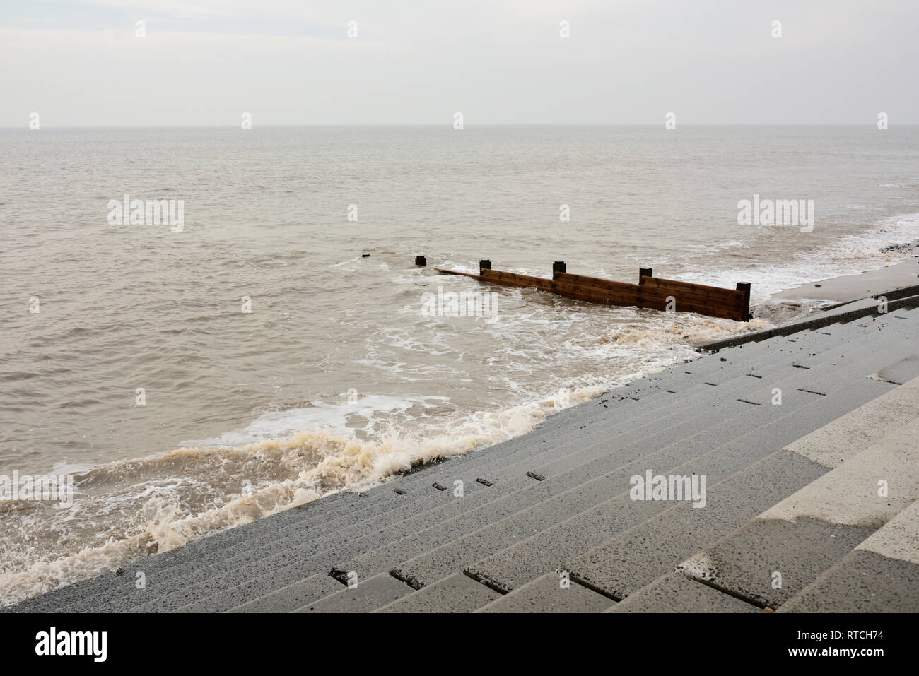 Irish sea lapping up against wooden groyne beach protection and ...