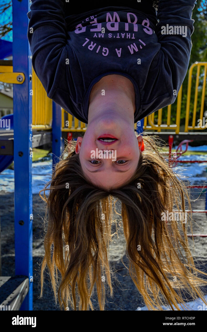 Girl hanging upside down on playground bars Stock Photo - Alamy