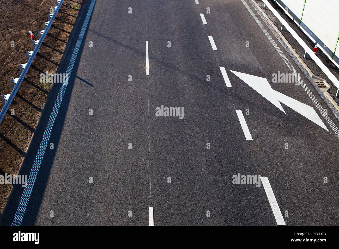 Newly laid asphalt road with an arrow ordering to take middle lane ...