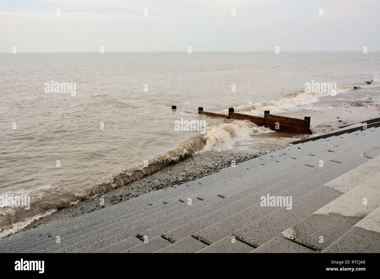 Irish sea lapping up against wooden groyne and stepped revetment in ...