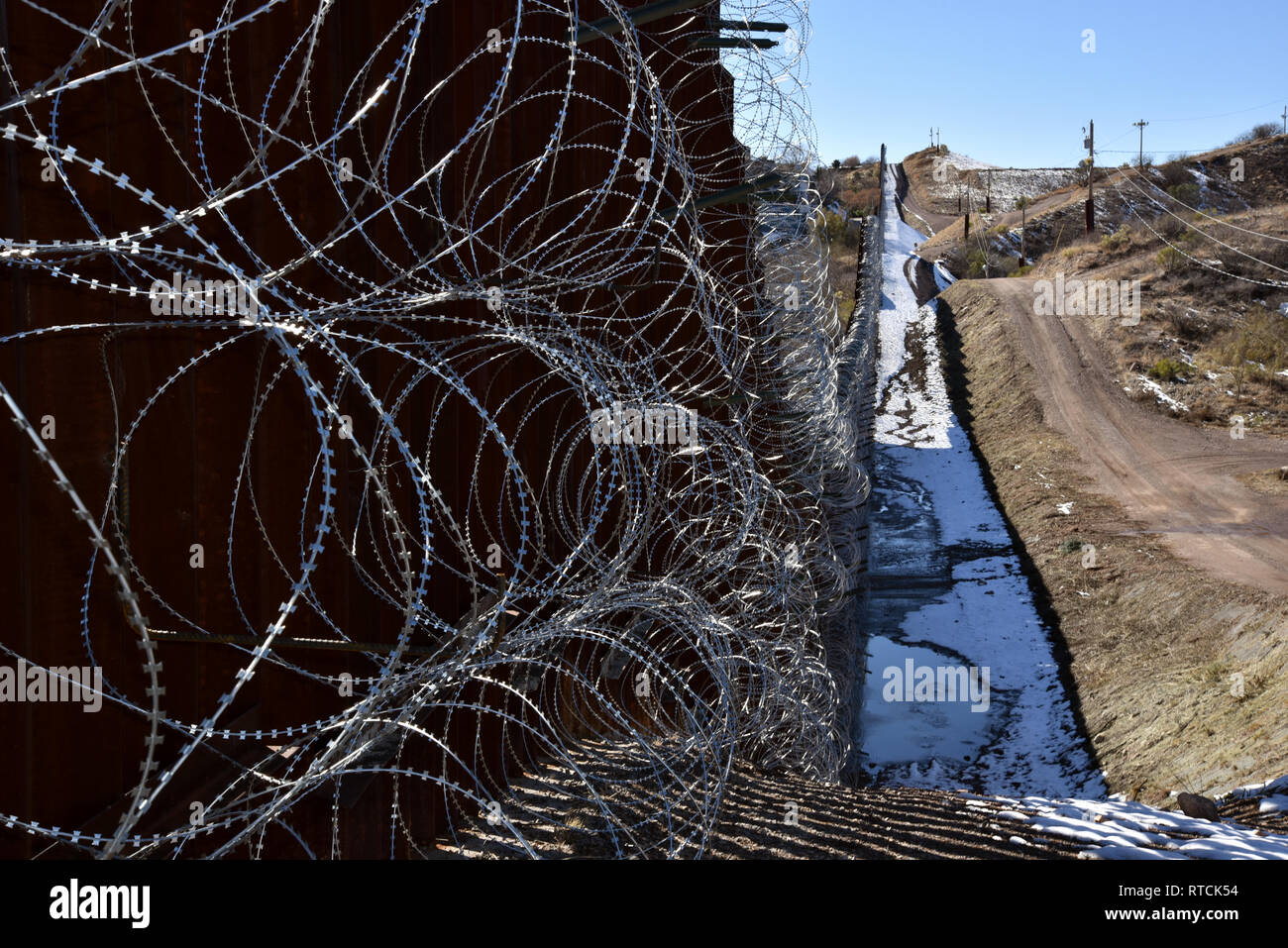 Four rows of concertina wire cover the metal wall in Nogales, Arizona ...