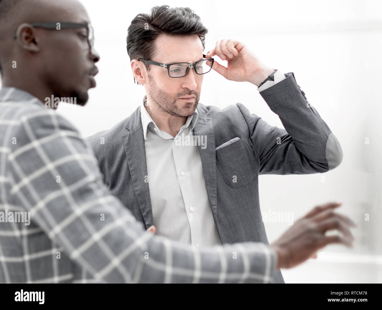 two serious businessmen talking standing in the office Stock Photo - Alamy