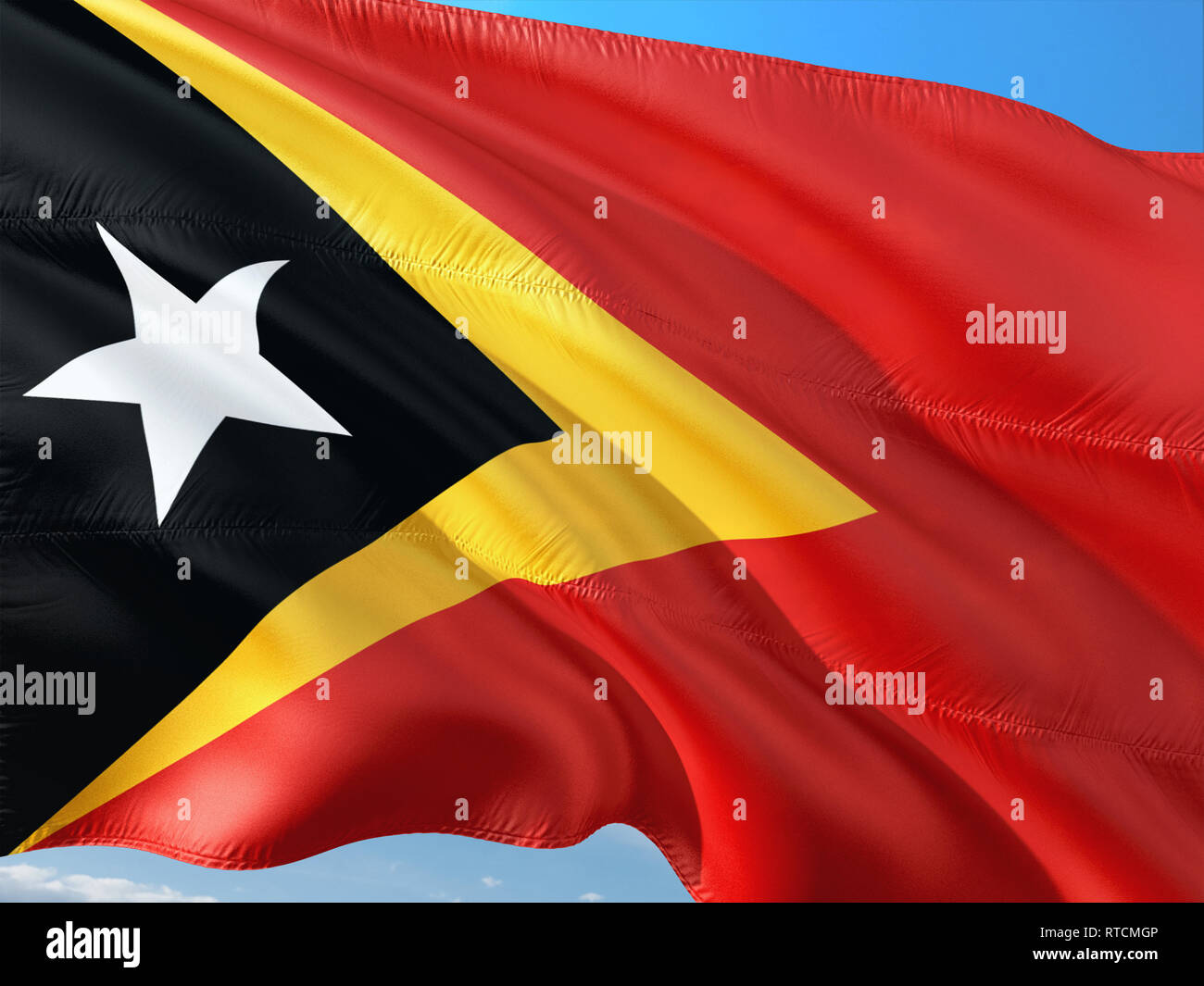 Flag of East Timor waving in the wind against deep blue sky. High ...
