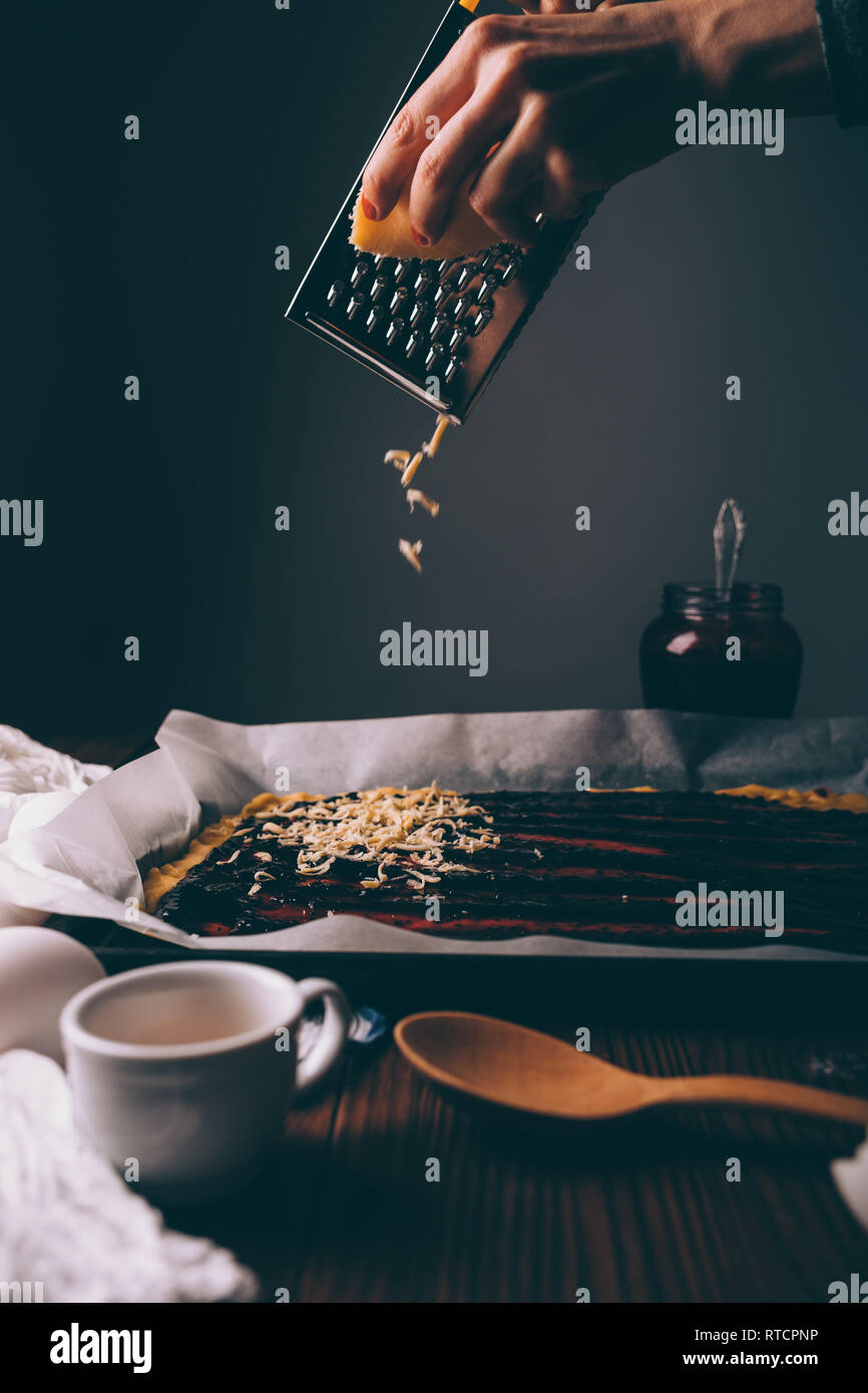 Process of cooking homemade grated pie. Woman's hands grind the frozen ...