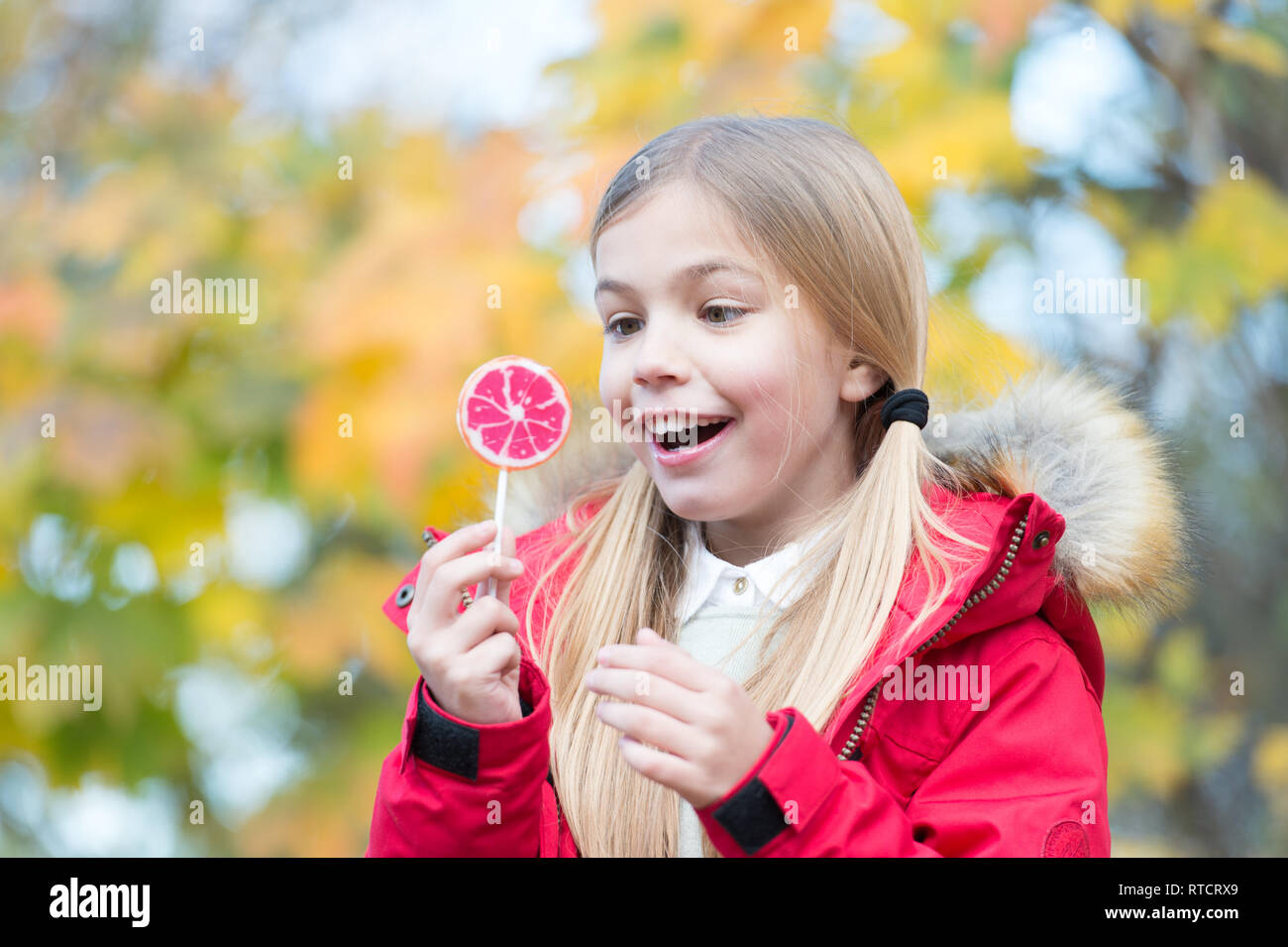 Food, dessert, snack. Child smiling with candy on stick outdoor. Girl ...
