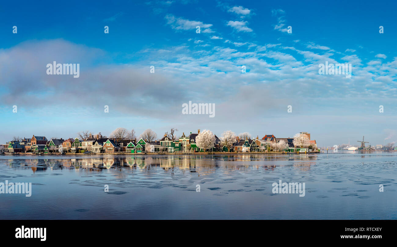 Houses at the bank of the river Zaan reflects in half frozen water ...