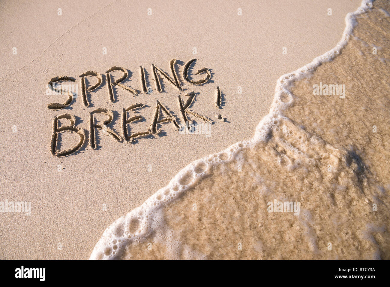 Excited Spring Break message handwritten on the smooth sand of an empty ...
