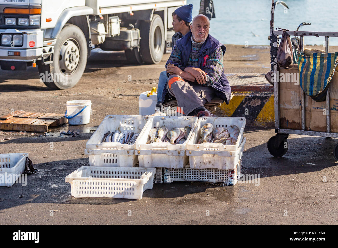 Fish vendor. Fish are gutted and offered for sale on the quay side in ...