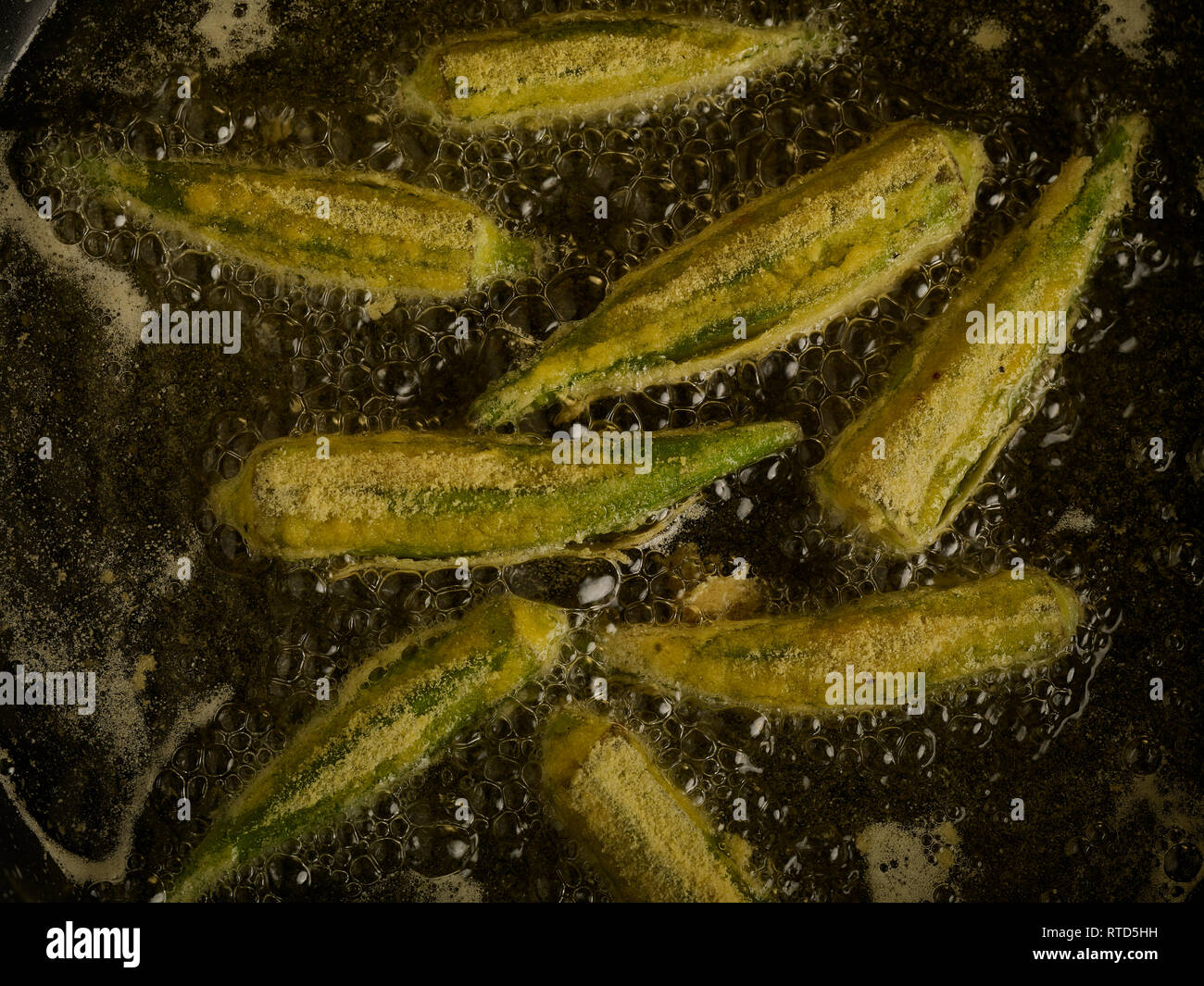 Spiced Okra frying in clean oil against a dark background food ...