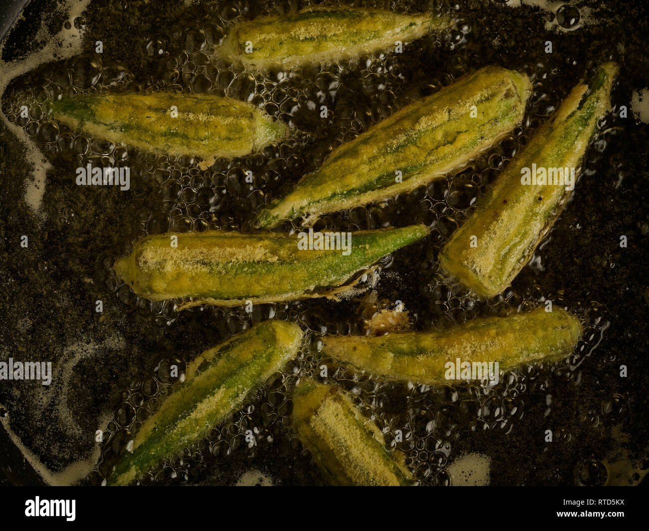 Spiced Okra frying in clean oil against a dark background food ...