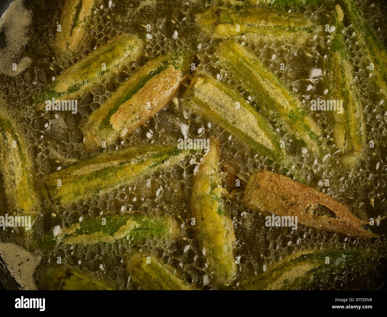 Spiced Okra frying in clean oil against a dark background food ...