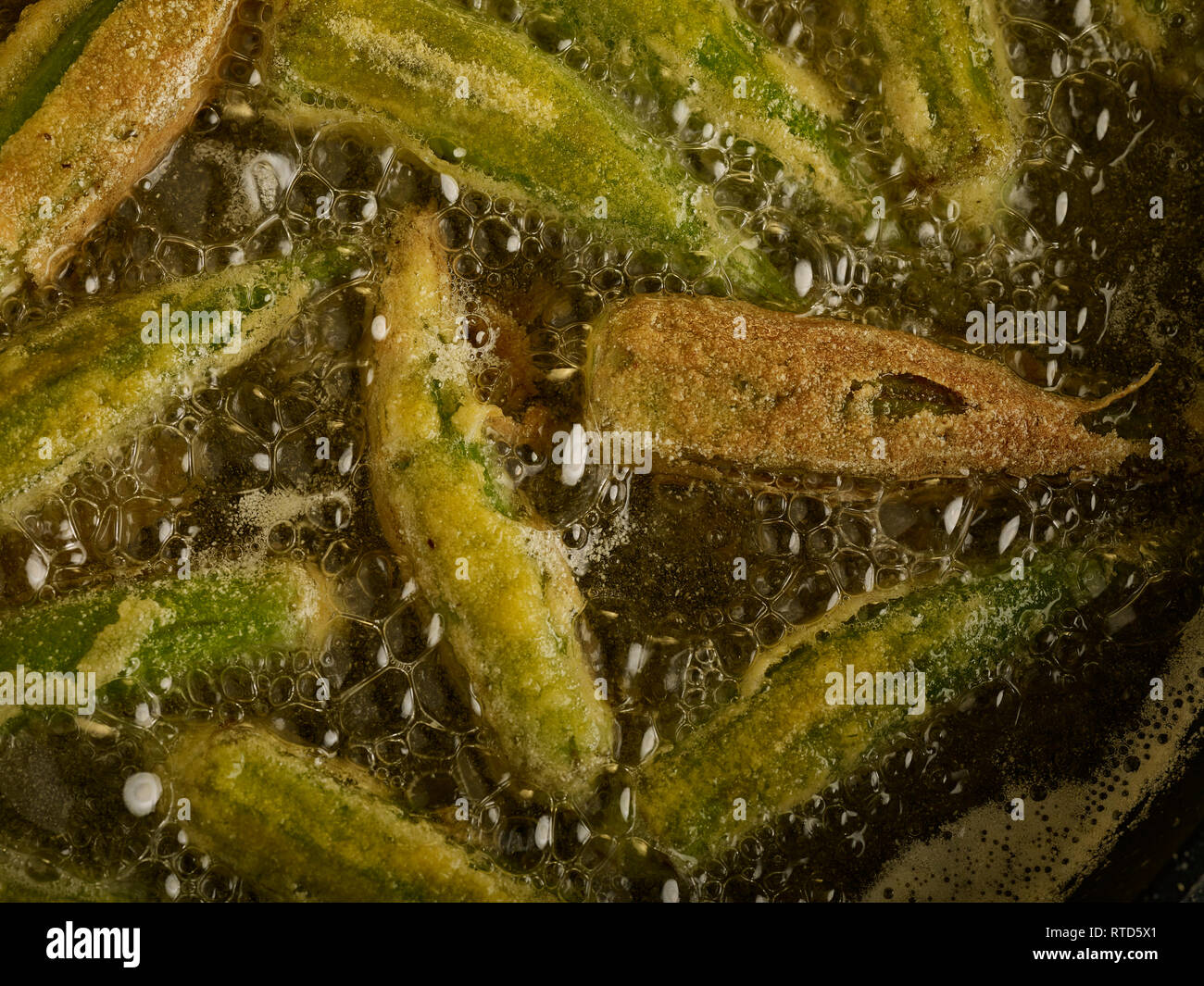 Spiced Okra frying in clean oil against a dark background food ...