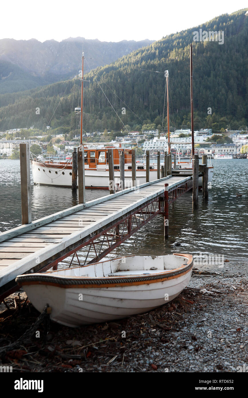 Sailing boat and tender tied to jetty in Lake Wakatipu, Queenstown ...