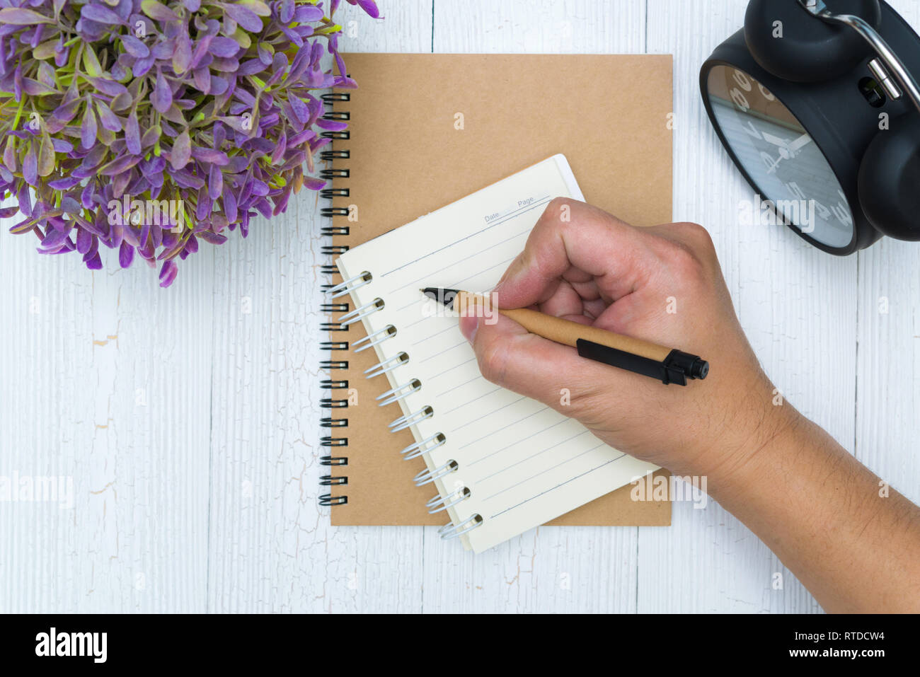 Man hand writing on blank page of notebook paper with pen on the wood ...