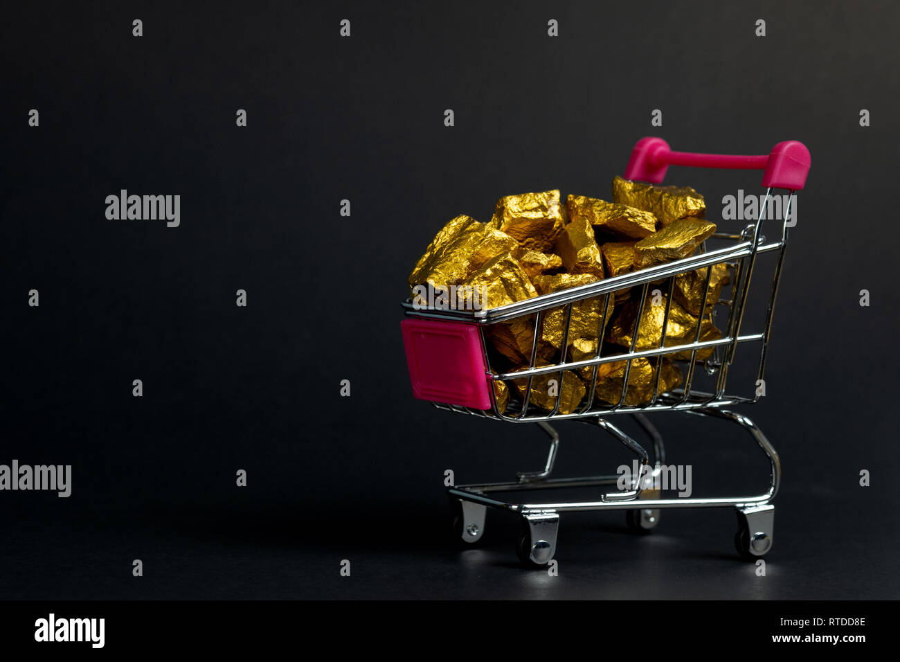 A pile of gold nuggets or gold ore in shopping cart or supermarket ...