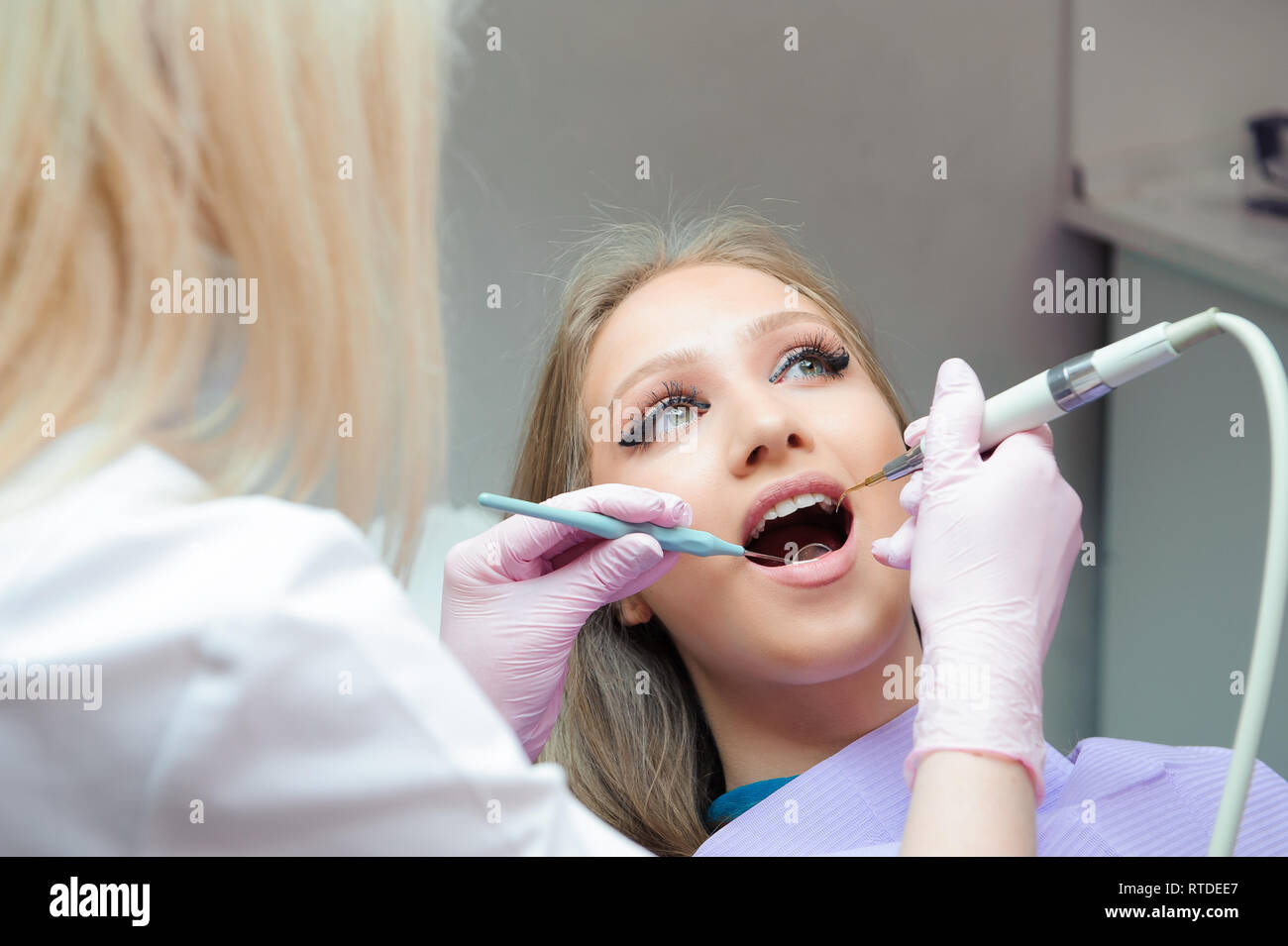 Doctor in uniform checking up female patient's teeth in dental clinic ...