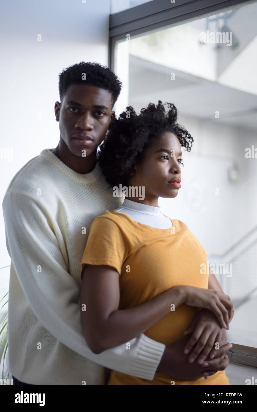 A young attractive black couple looking serious in a simple white room ...