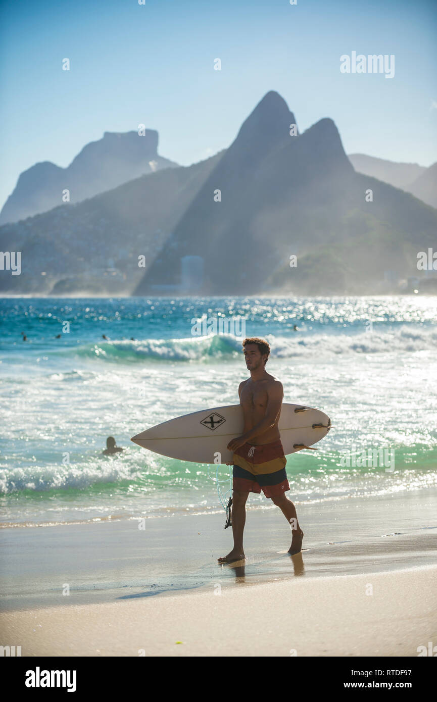 RIO DE JANEIRO - MARCH 20, 2017: A young Brazilian surfer carries his ...