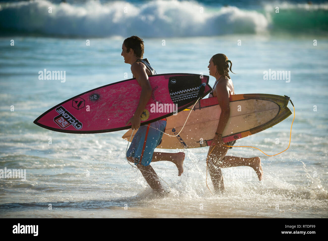 RIO DE JANEIRO - FEBRUARY 9, 2017: A pair of surfers run with ...