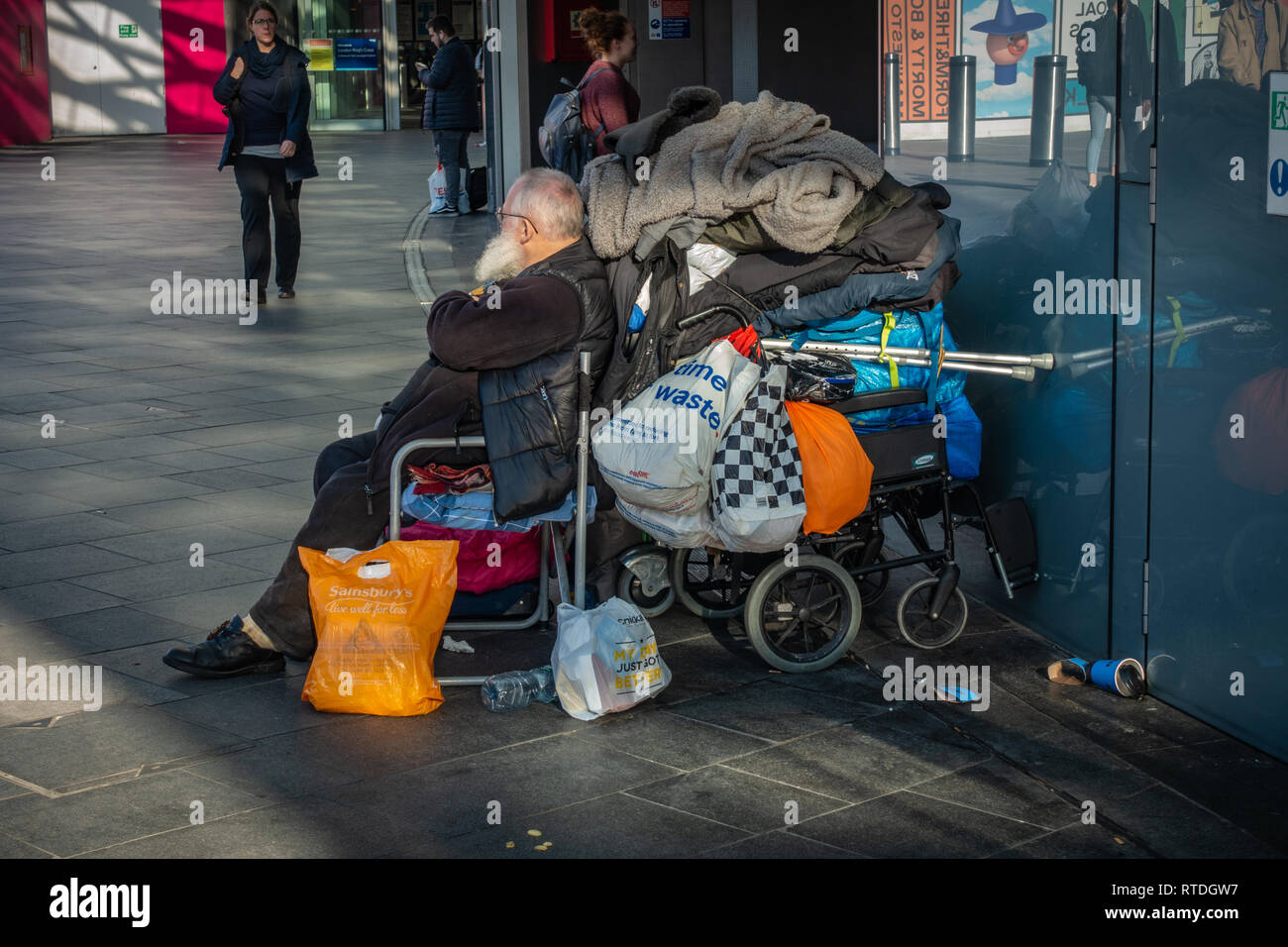 Old Homeless man sitting in his chair surounded by all his many items ...