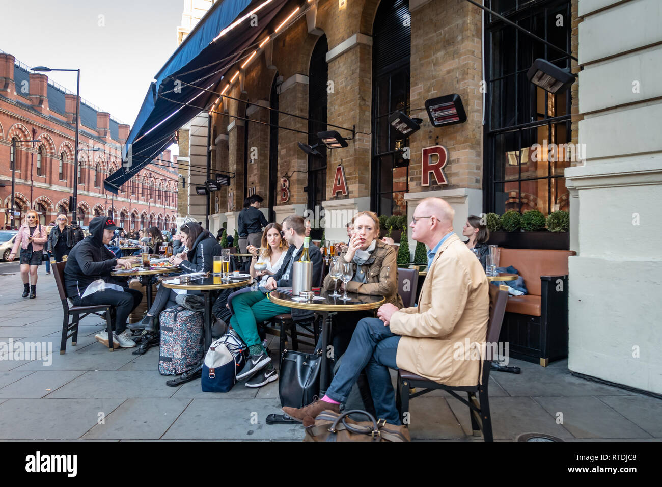 People sitting outside a bar next to Kings Cross Railway Station ...