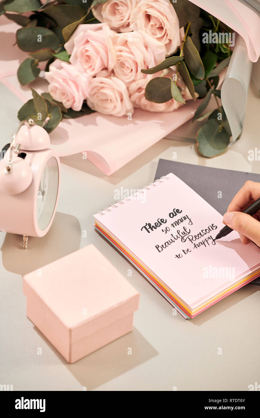 Woman hands holding pen, ready to write. Pink rose, pen and gift with ...