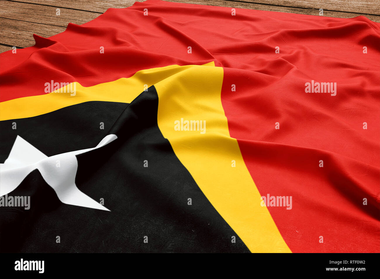Flag of East Timor on a wooden desk background. Silk East Timorese flag ...