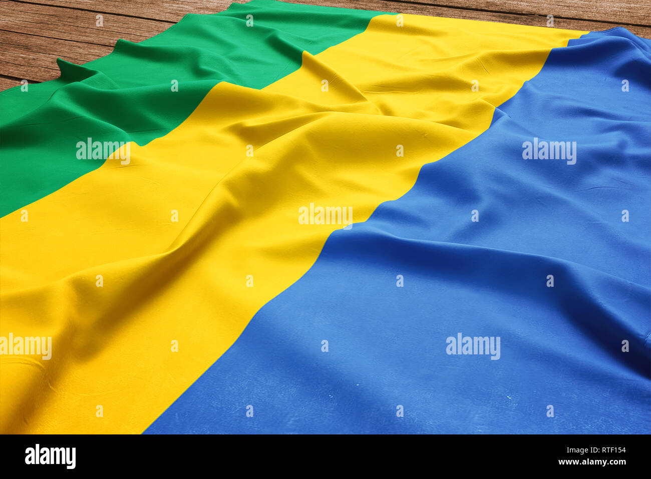 Flag of Gabon on a wooden desk background. Silk Gabonese flag top view ...