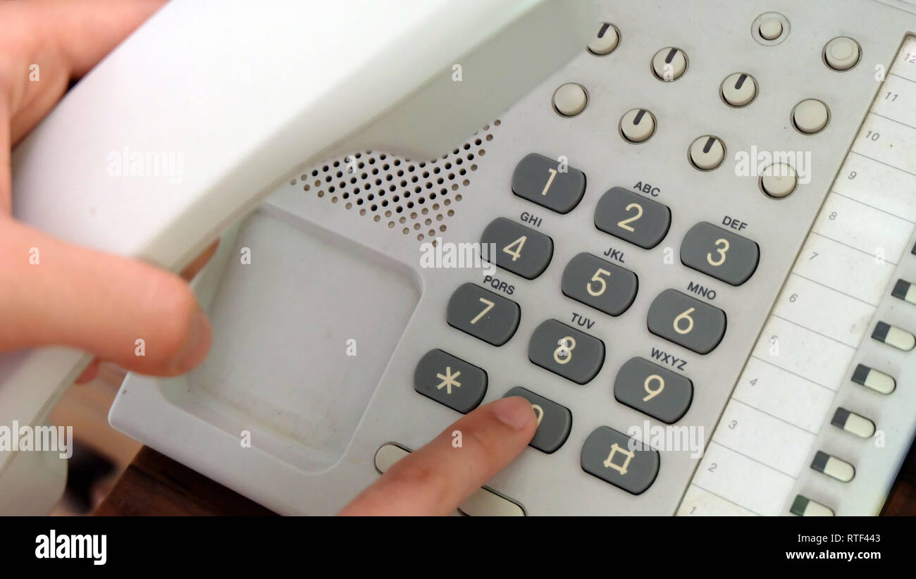Finger dialing an office dial phone with many buttons when another hand ...
