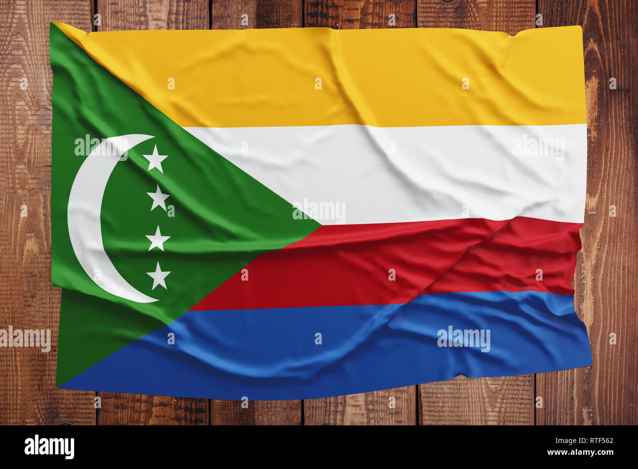 Flag of Comoros on a wooden table background. Wrinkled Comoran flag top ...