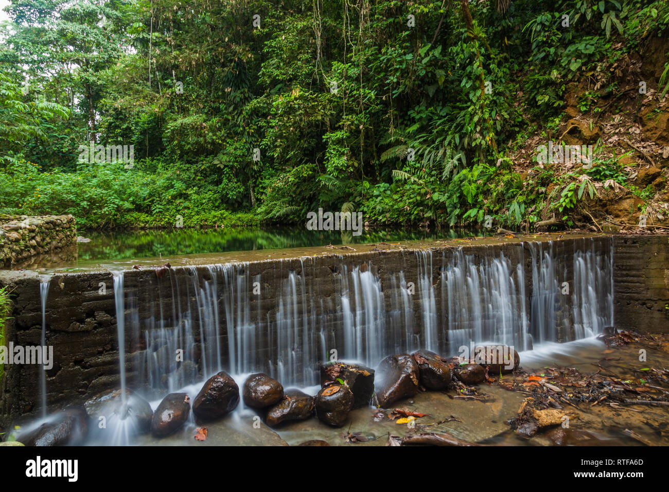 Small artificial waterfall in a beautiful river surrounded by jungle ...