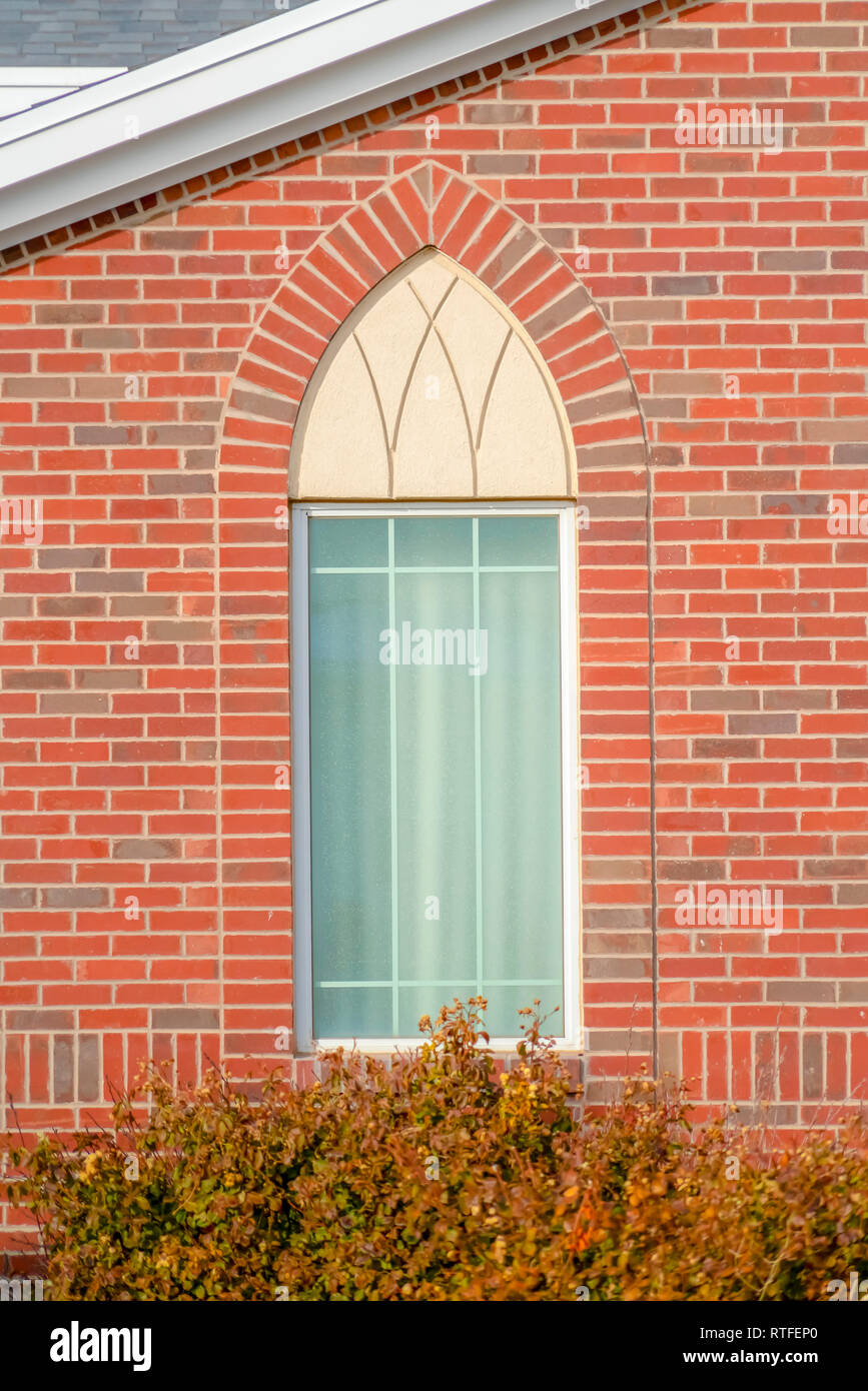 Arched window of a church with red brick wall. Close up view of the ...