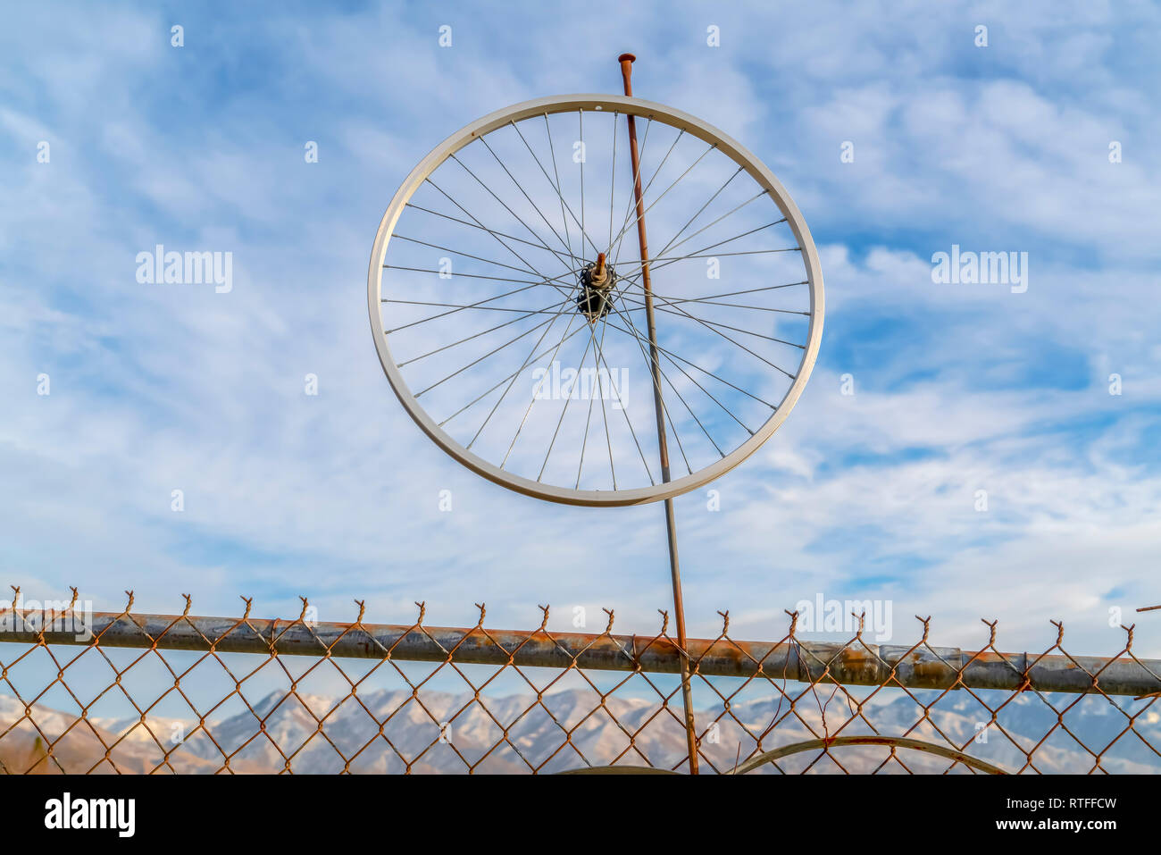 Bike wheel rim above a fence with sky background. Bicycle wheel rim ...